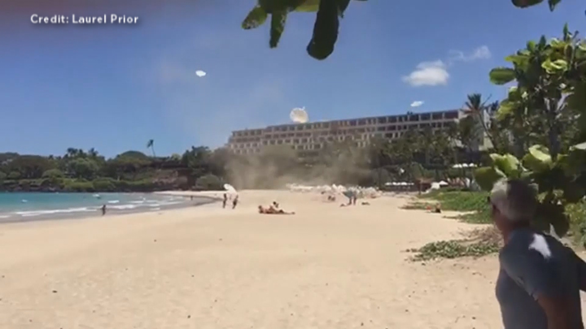 Dust devil sends beach umbrellas flying and Hawaiian beach goers ...